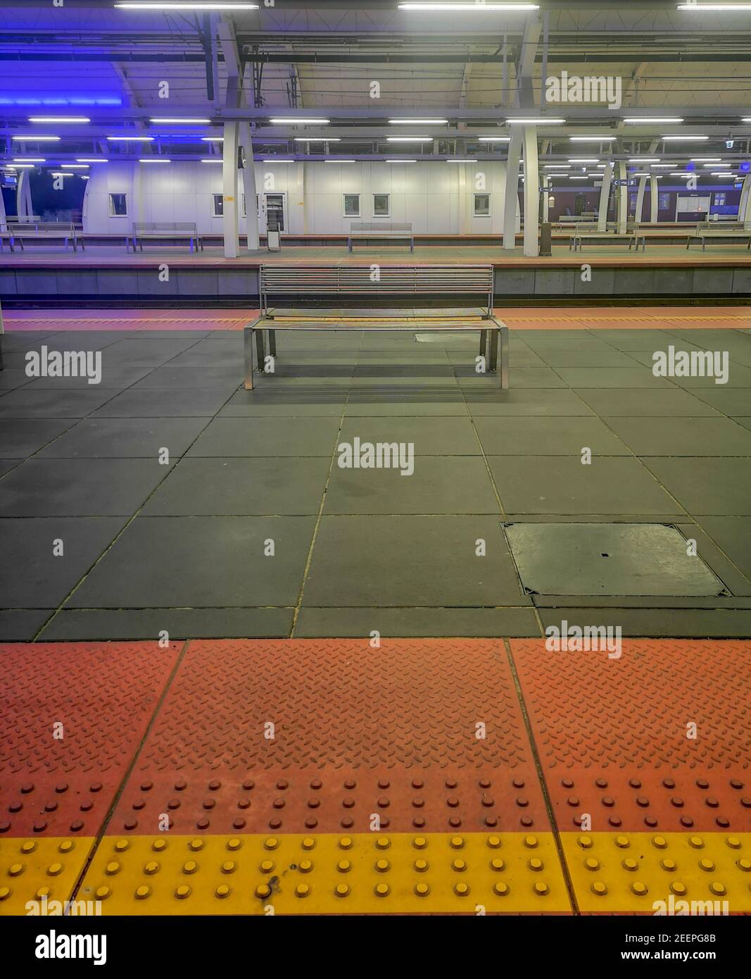 Metal bench on train station with colorful lights and red, yellow and ...