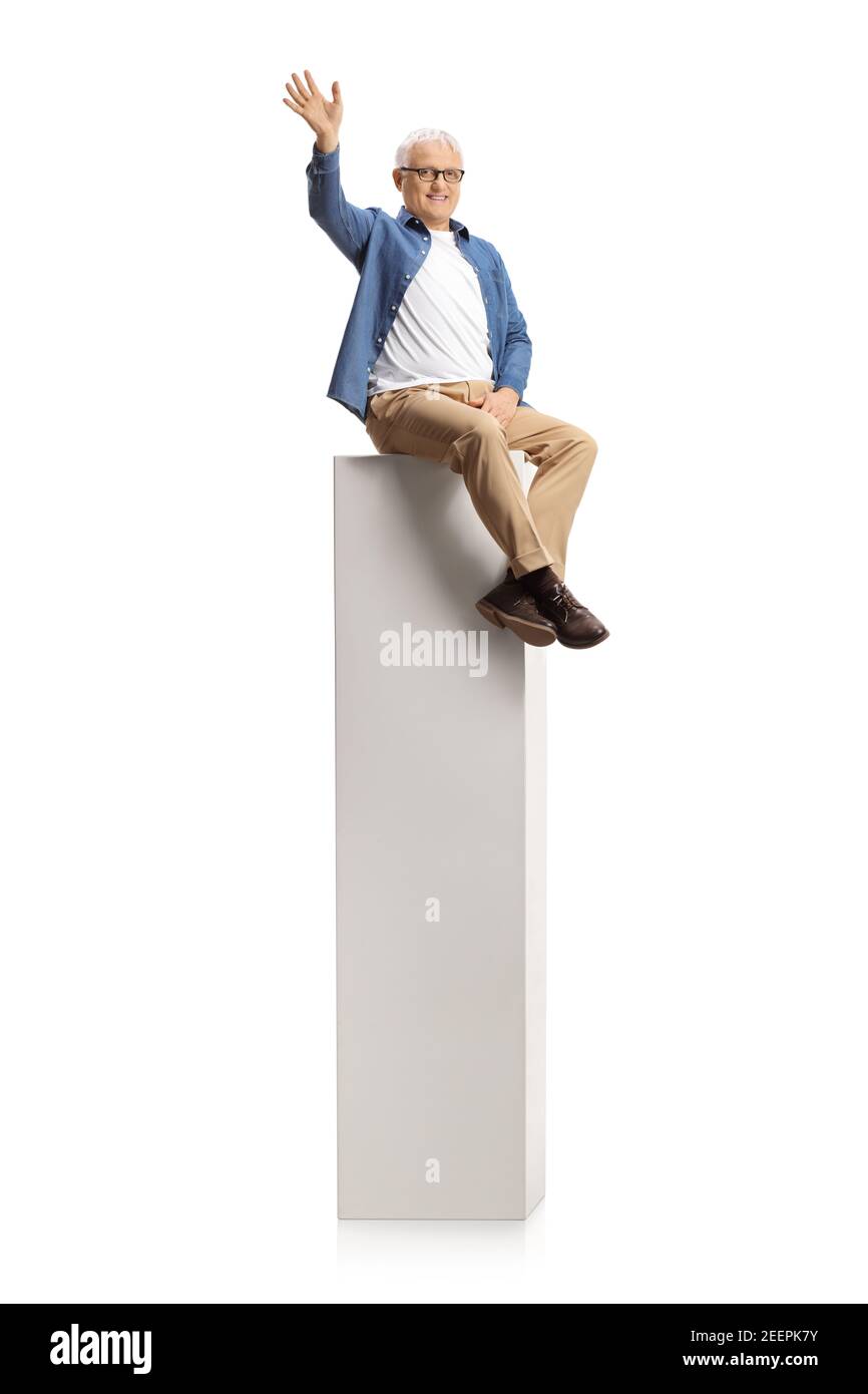 Smiling mature man sitting on a column and waving at camera isolated on ...