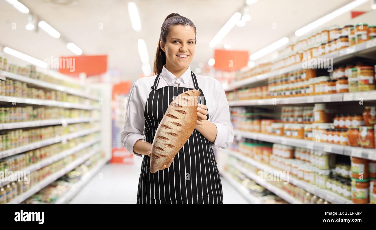 Female shop assistant holding a bread loaf inside a supermarket Stock ...