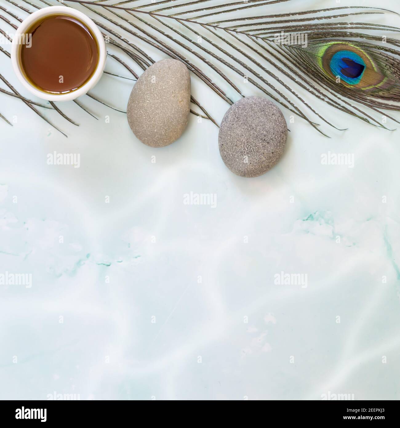 Flat lay composition with peacock feather, massage stones, oil on a ...