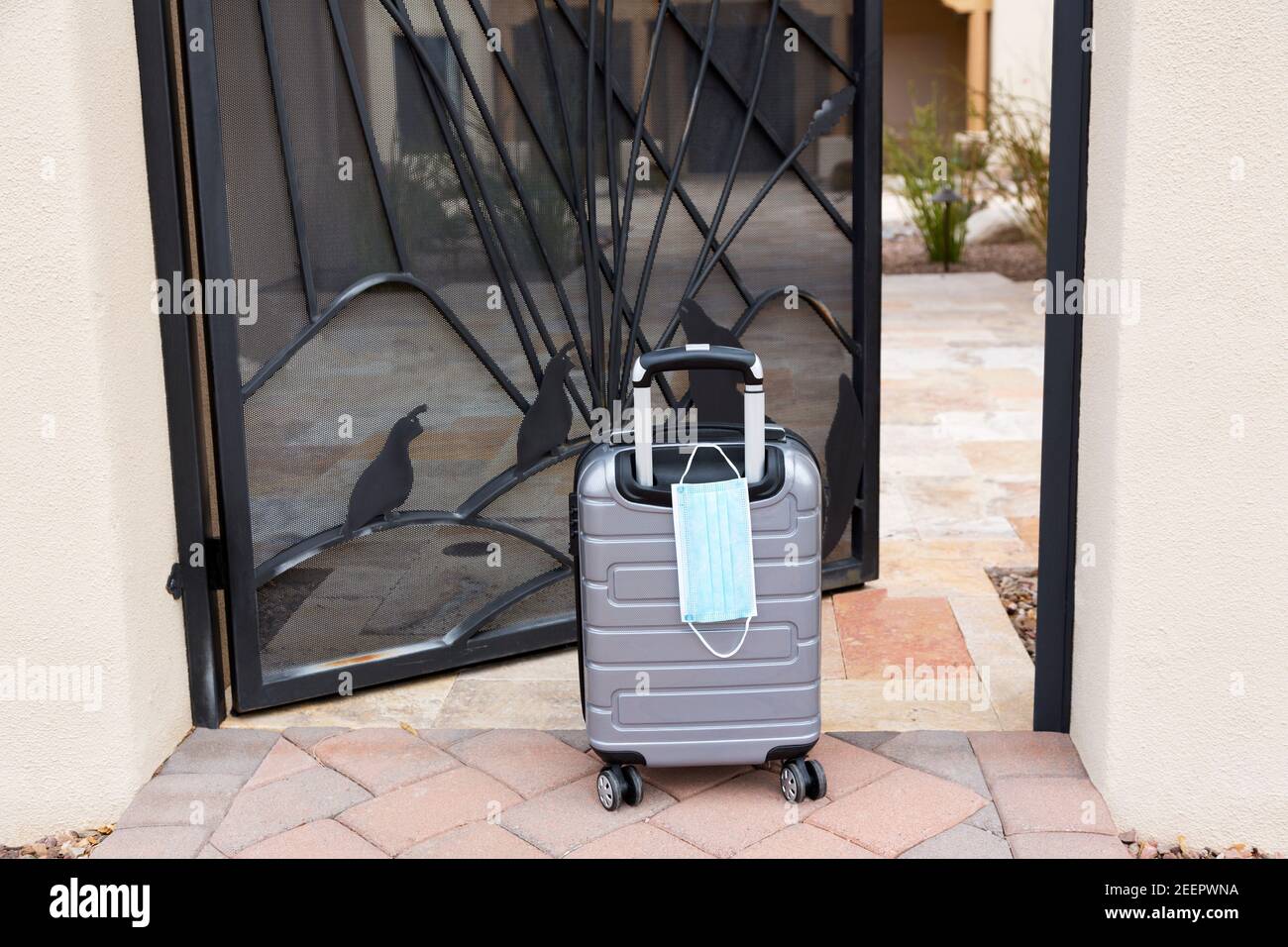 Open gate from courtyard with suitcase and face mask in front show ...