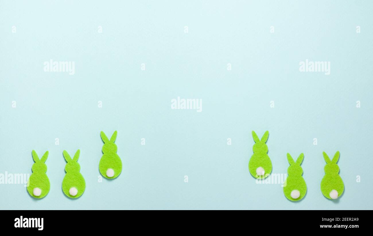 Green velvet bunnies with white tails on bright blue background at the ...