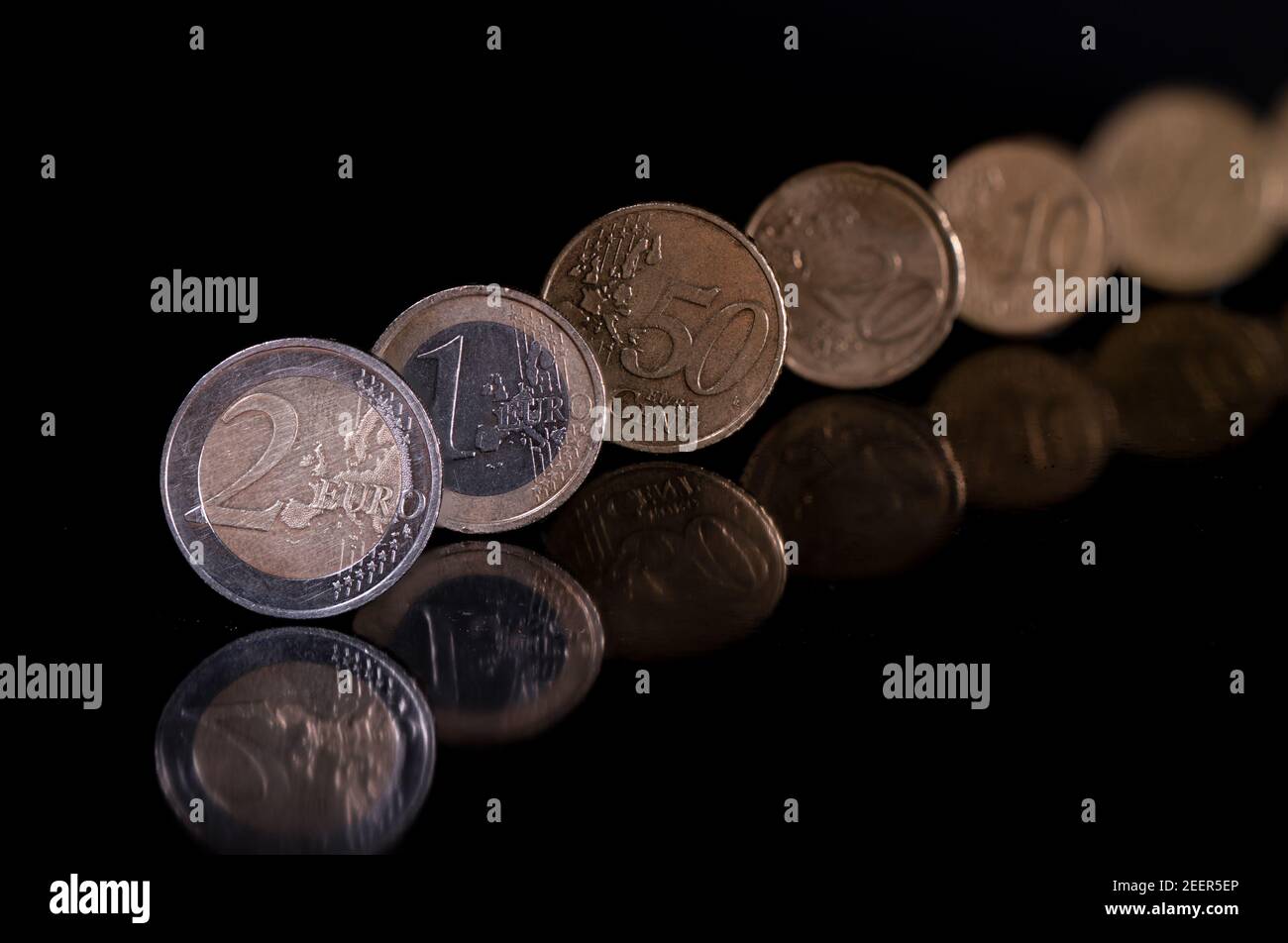 Euro coins standing on the edge isolated with pitch black background ...