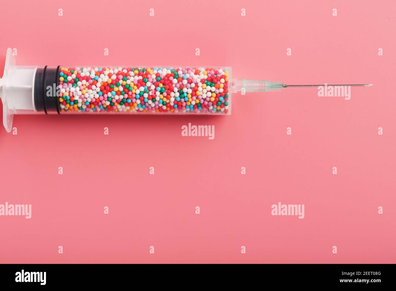 Syringe filled with colorful nano balls on a pink background ...