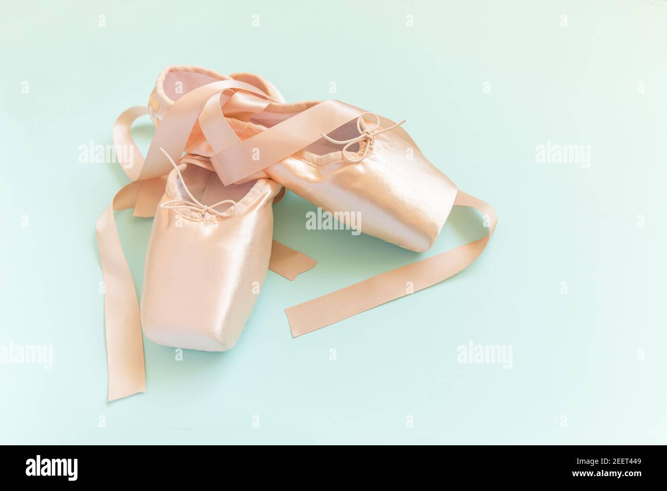 New pastel beige ballet shoes with satin ribbon isolated on blue ...
