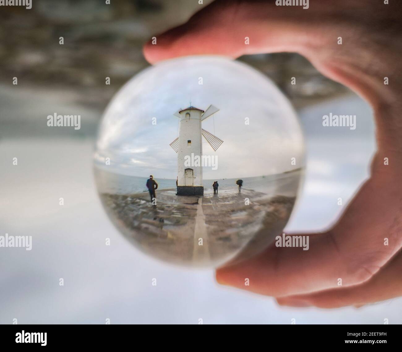 White Windmill at end of coast full of puddles near Baltic sea in ...