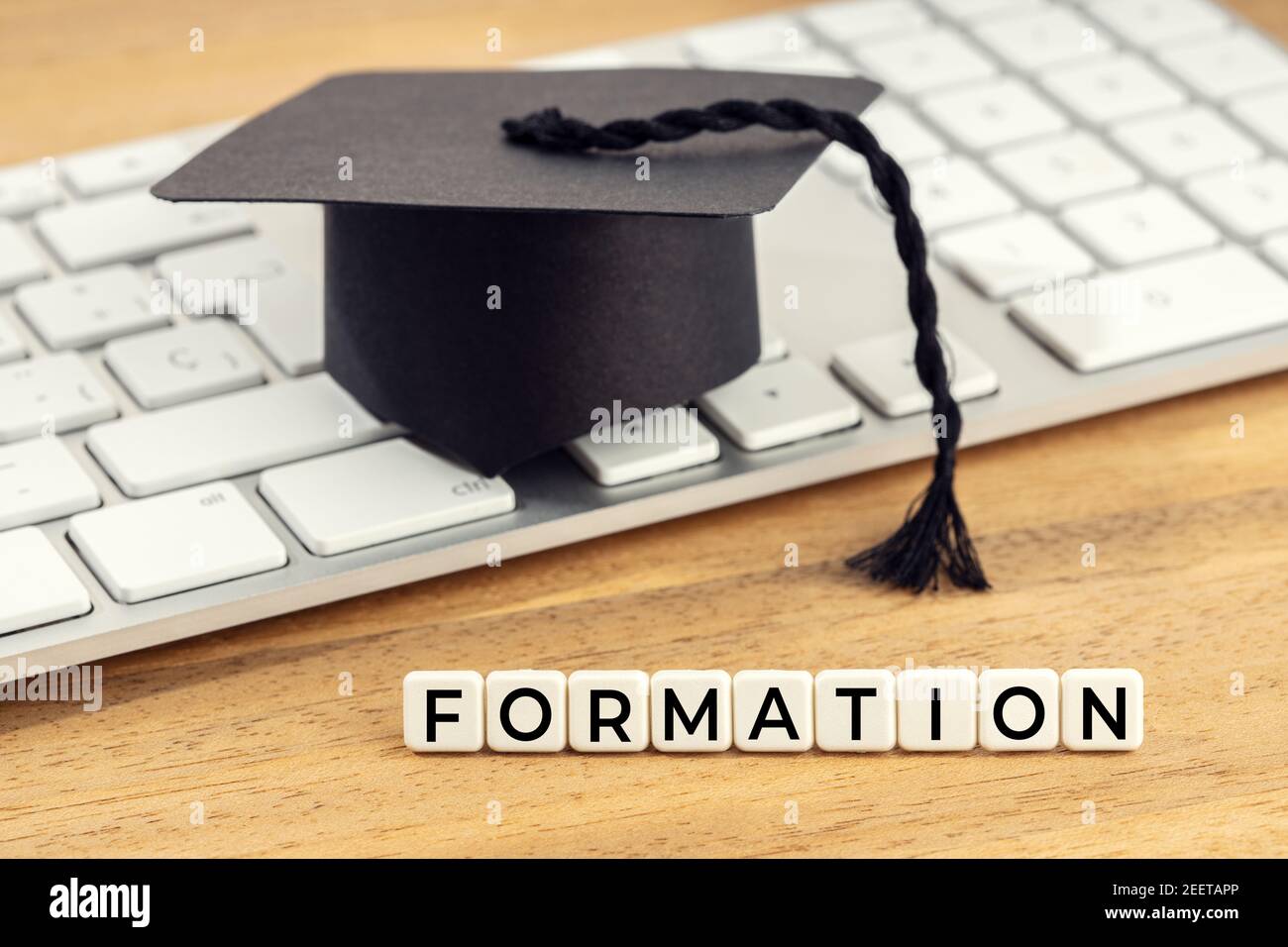 Formation concept. Graduation cap on computer keyboard on wooden desk ...