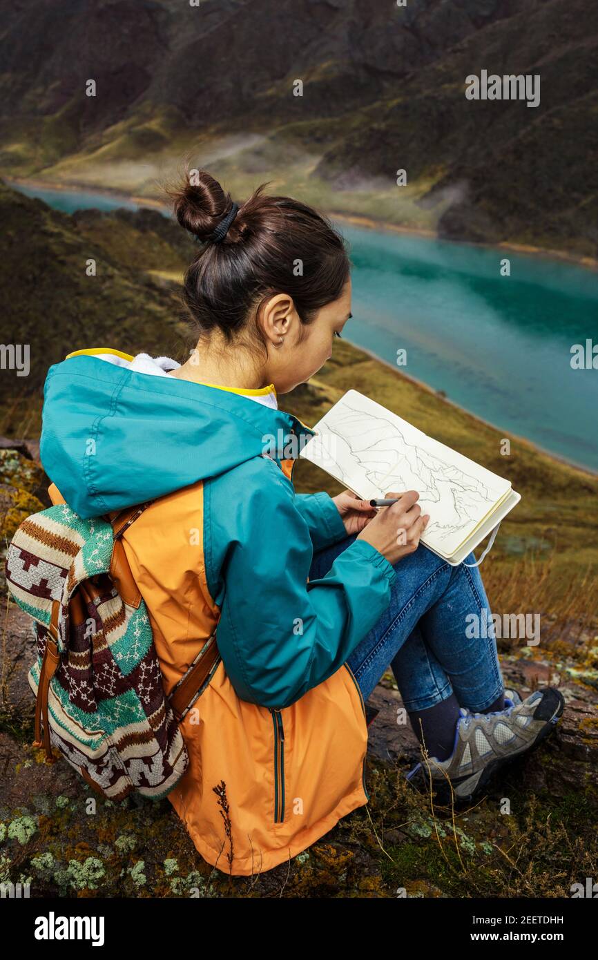 Girl draws on nature spring landscape. A girl sits on a rock by the ...