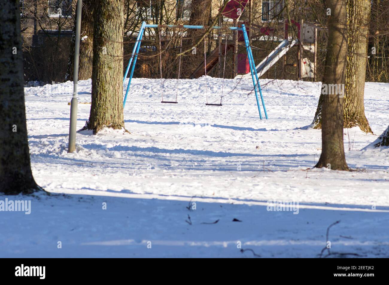 Swing at playground for children in a public park in winter with snow ...