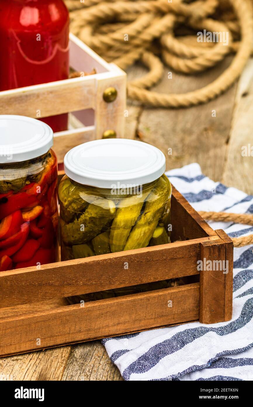 Wooden crate with glass jars with pickled red bell peppers and pickled ...