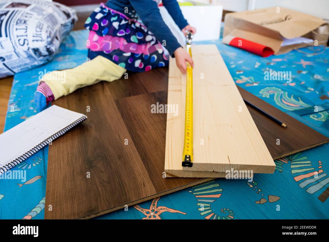 Detail of child helping with measuring wooden plank to make shelves ...