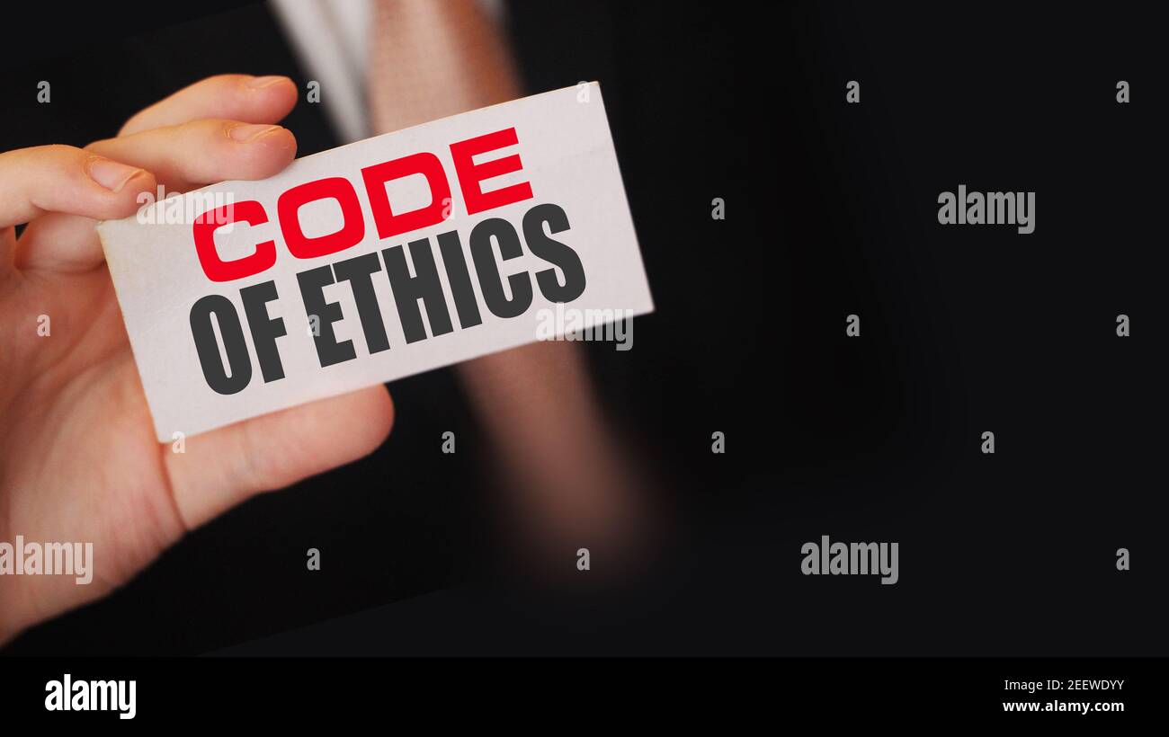 Businessman shows a card with text Code of ethics Stock Photo - Alamy