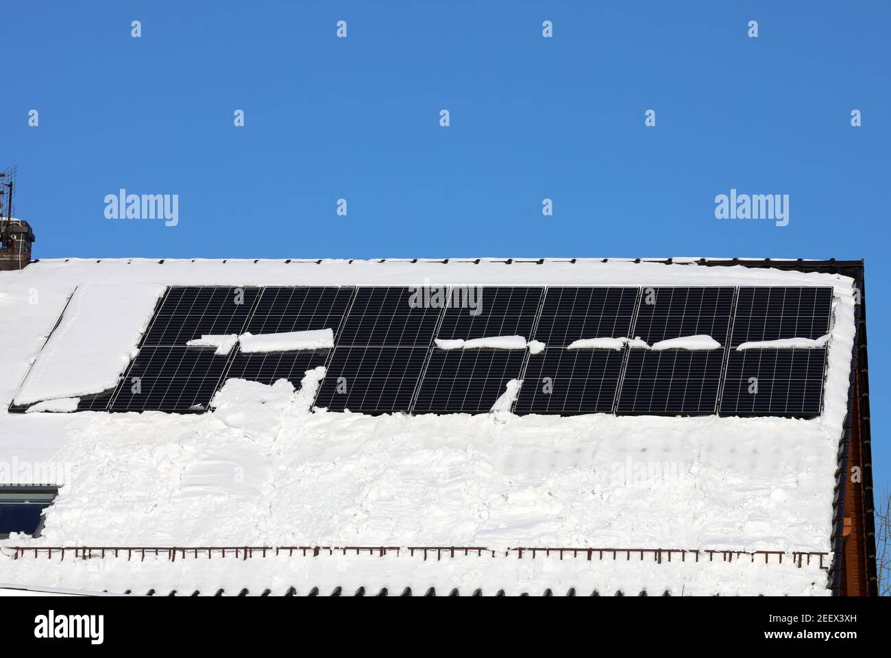 Photovoltaic panel partially covered with snow in winter in a private ...