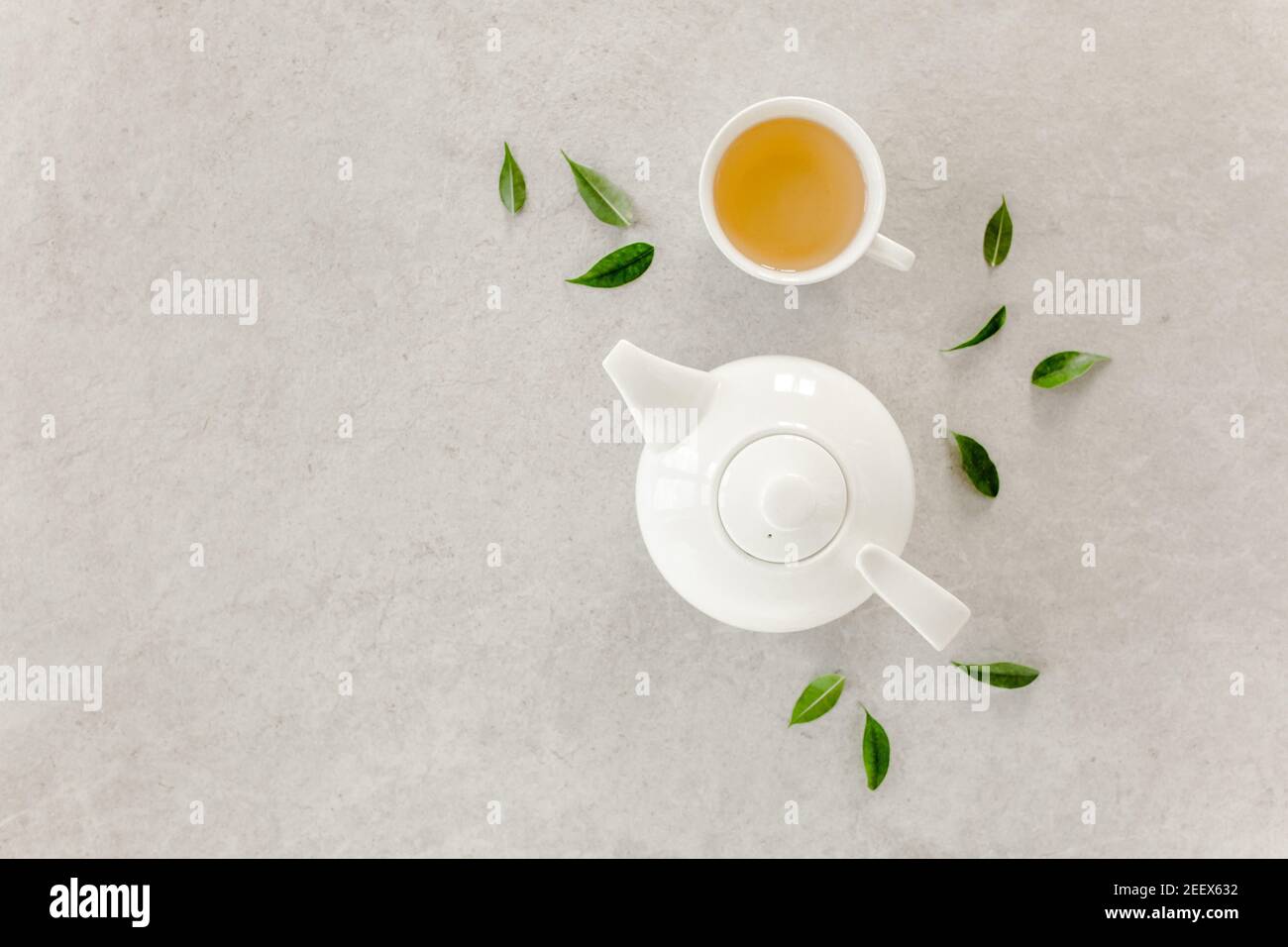 Herbal tea with two white tea cups and teapot, with green tea leaves ...