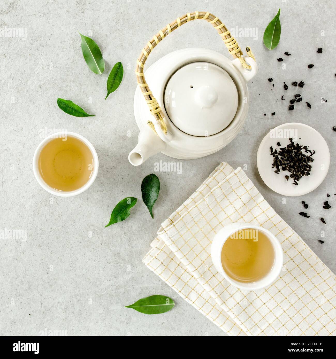 Herbal tea with two white tea cups and teapot, with green tea leaves ...