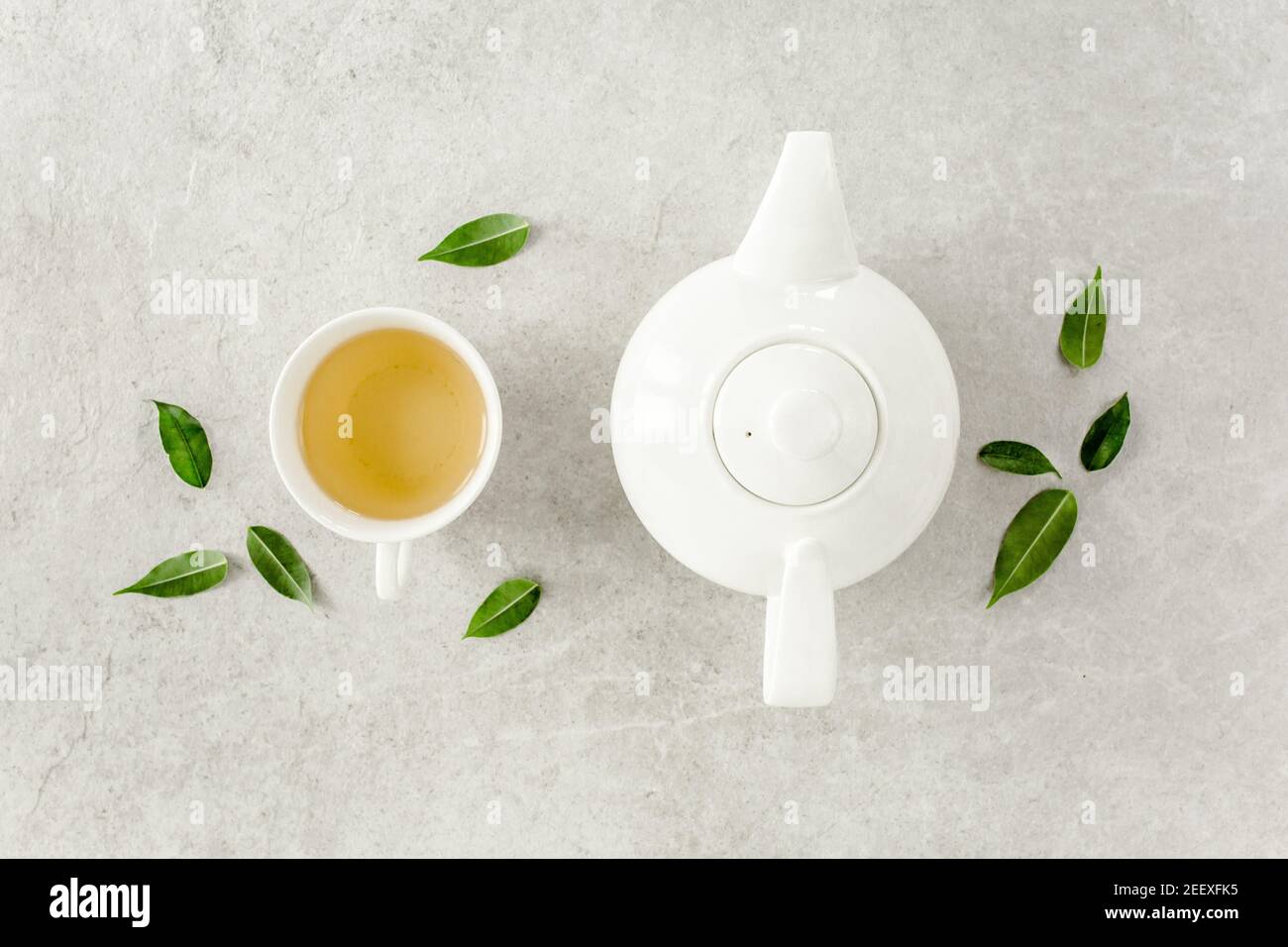 Herbal tea with two white tea cups and teapot, with green tea leaves ...