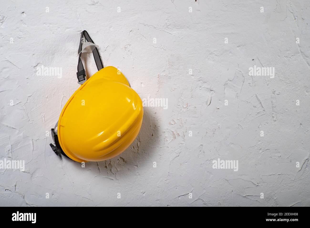 Yellow work helmet hung on a hook. Health and safety accessories on a ...