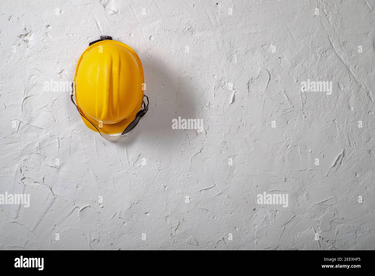 Yellow work helmet hung on a hook. Health and safety accessories on a ...