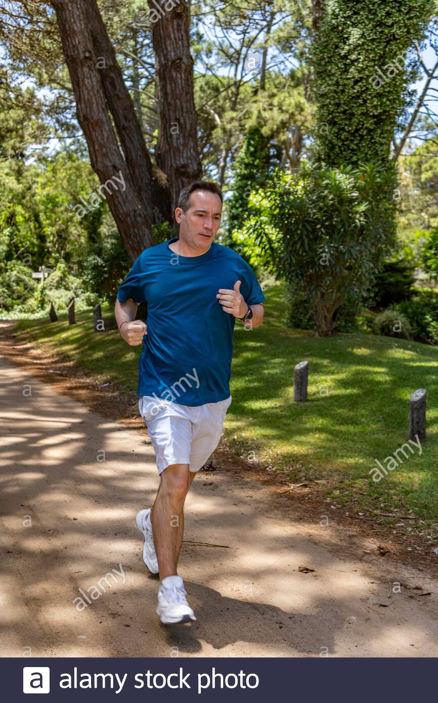Man running on road in the woods training for marathon Stock Photo - Alamy