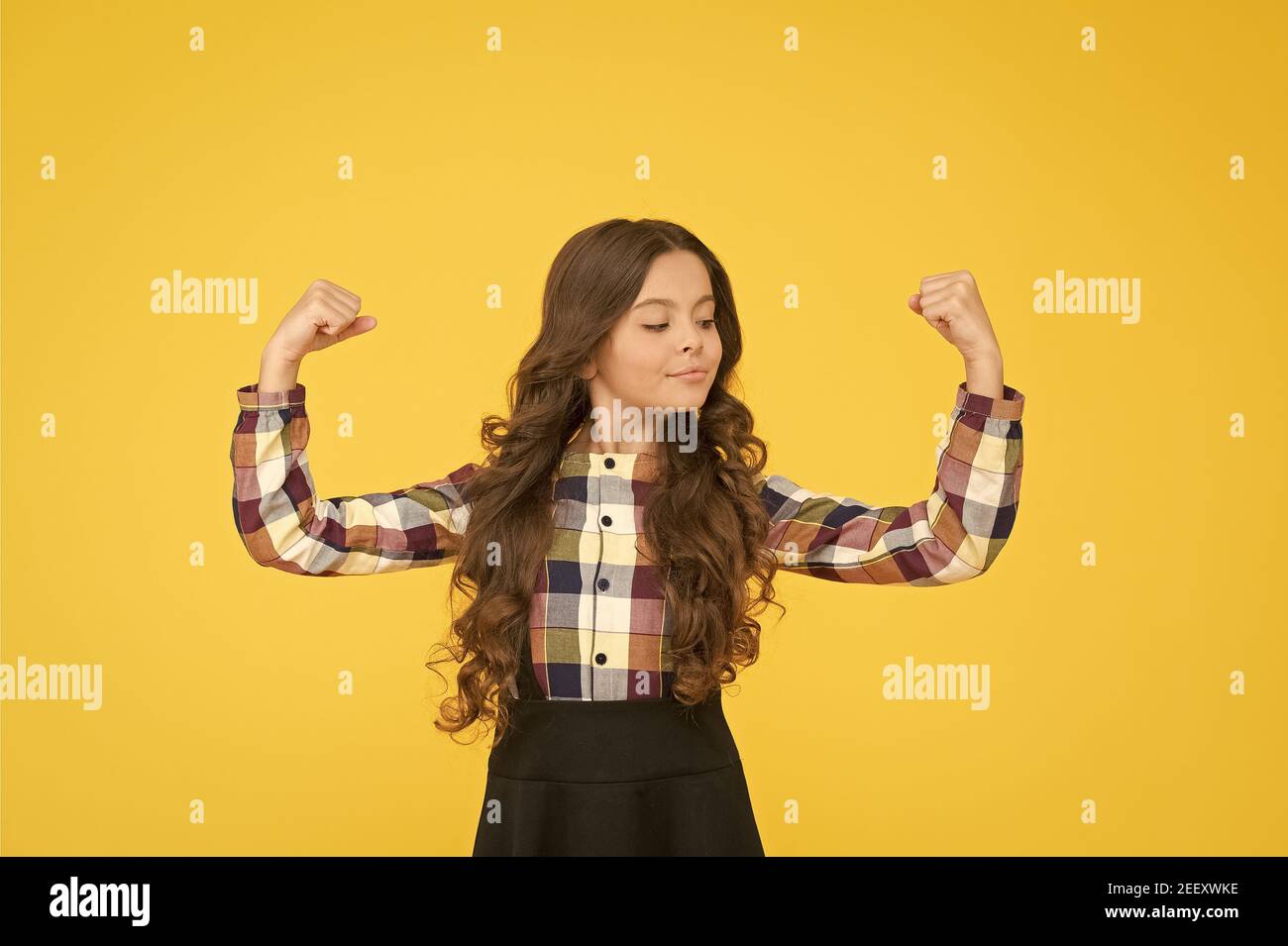 Showing off her power. Little girl flex arms yellow background. School ...