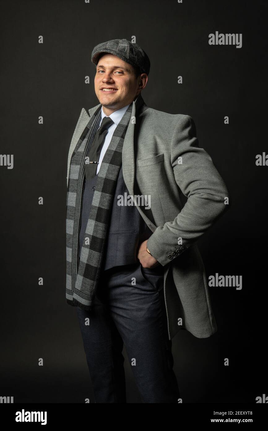in a coat and a cap a scarf Young man three piece suit confident ...