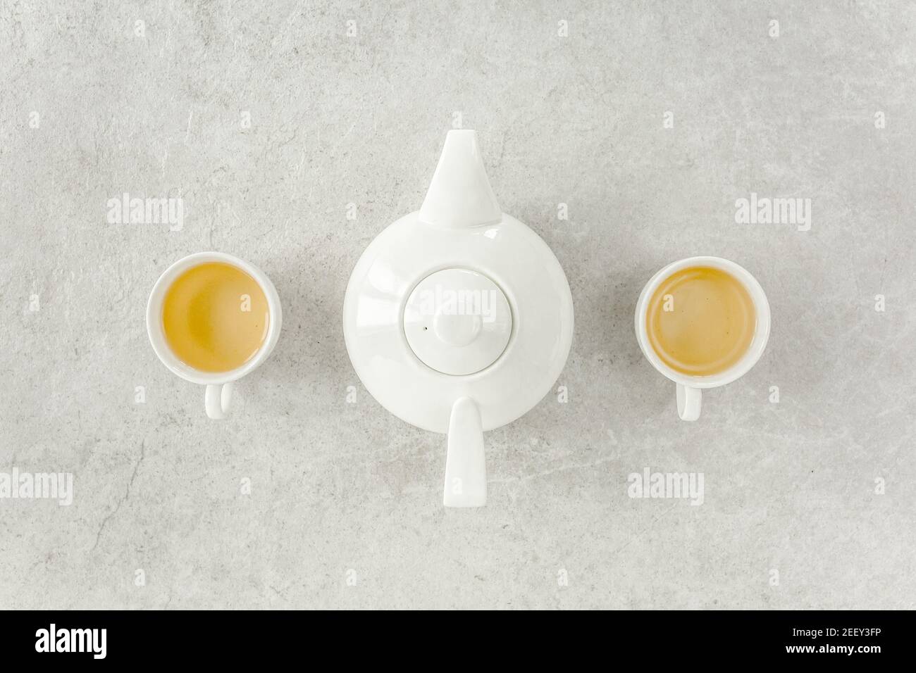 Herbal tea with two white tea cups and teapot, with green tea leaves ...