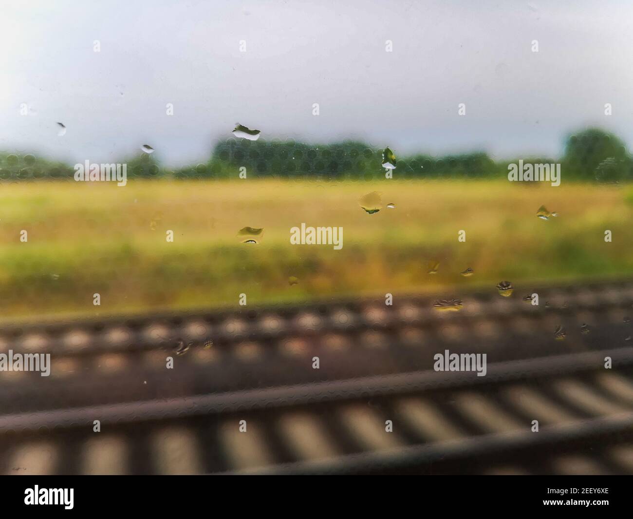 Rainy drops on train window at travel with rails and landscape behind ...