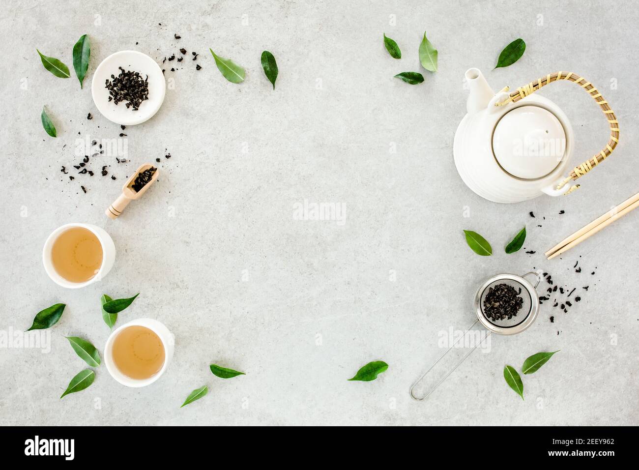 Herbal tea with two white tea cups and teapot, with green tea leaves ...