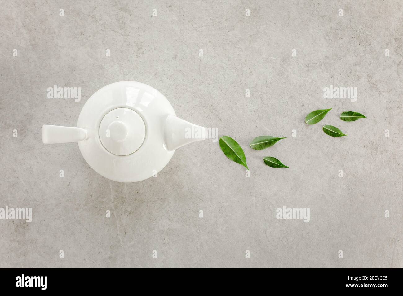 Herbal tea in a white teapot, with green tea leaves. Flat lay, top view ...