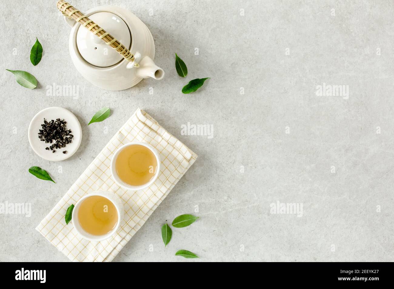 Herbal tea with two white tea cups and teapot, with green tea leaves ...