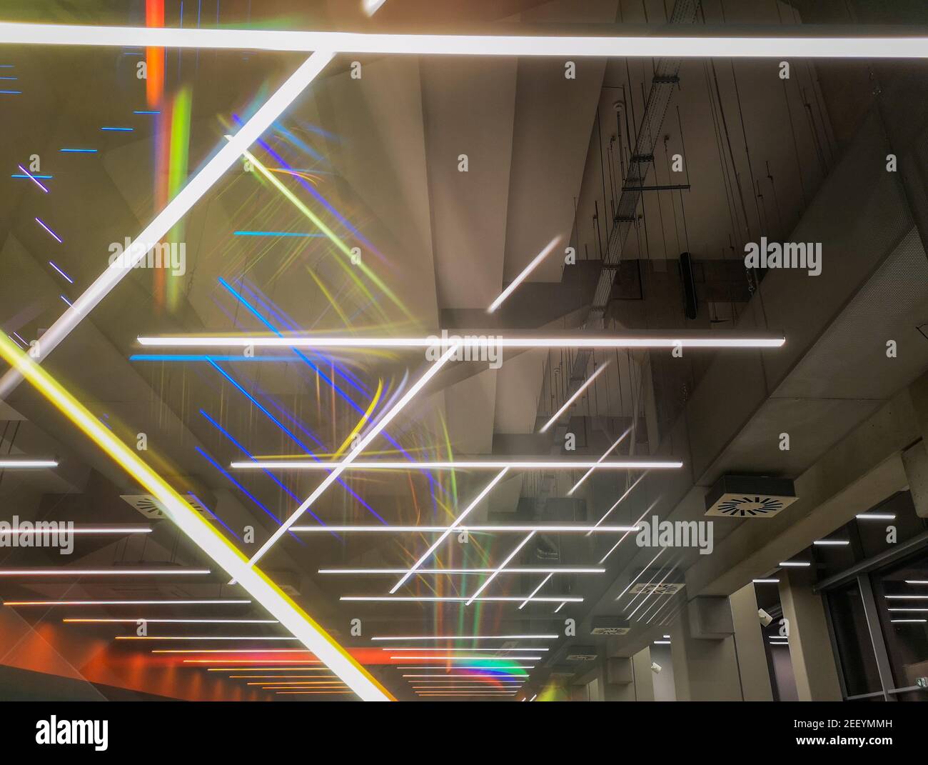 Glowing lamps in prism look hanging under ceiling and ventilation ducts ...