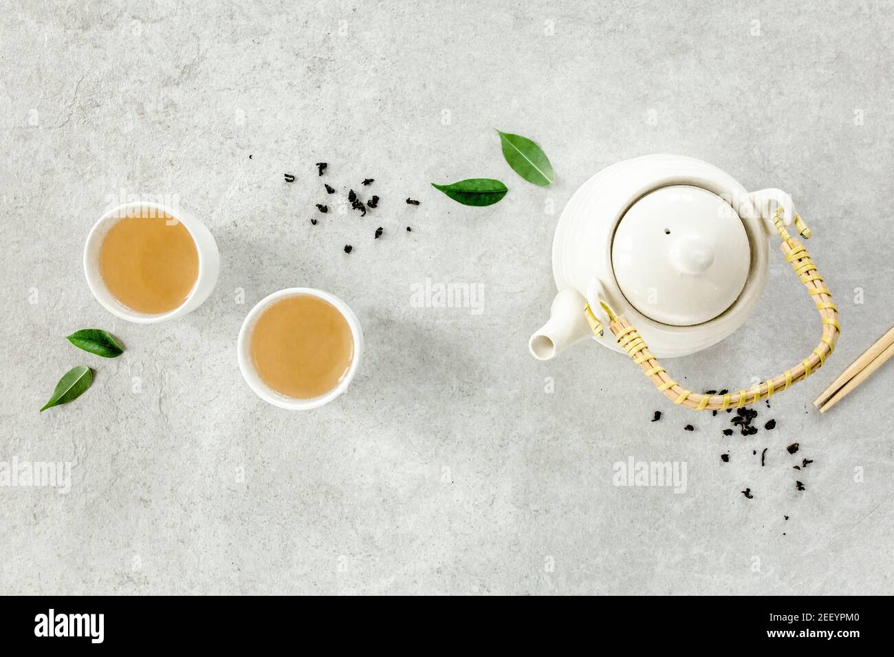 Herbal tea with two white tea cups and teapot, with green tea leaves ...