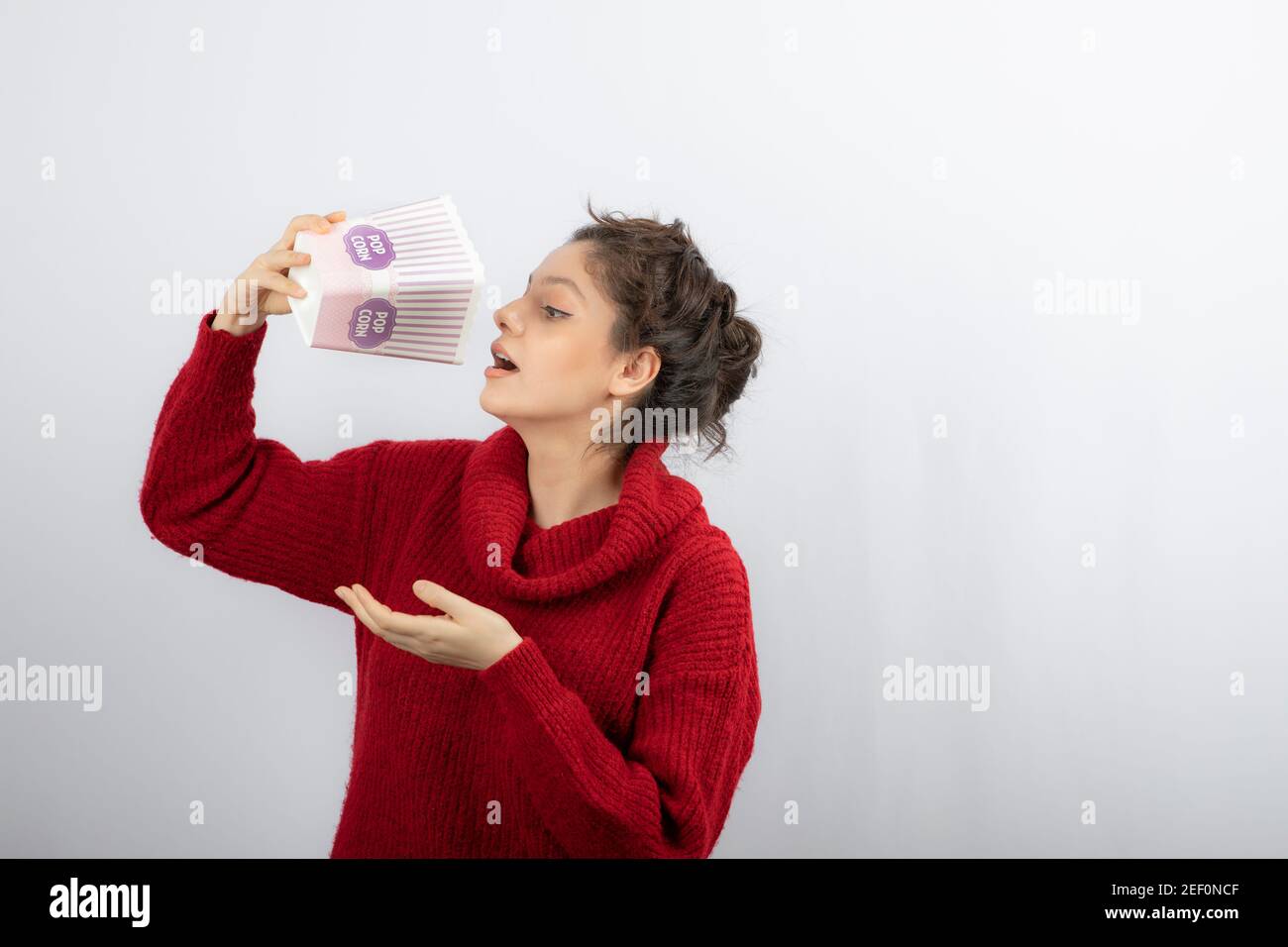 Photo of a cute woman looking into a bucket with popcorn Stock Photo ...