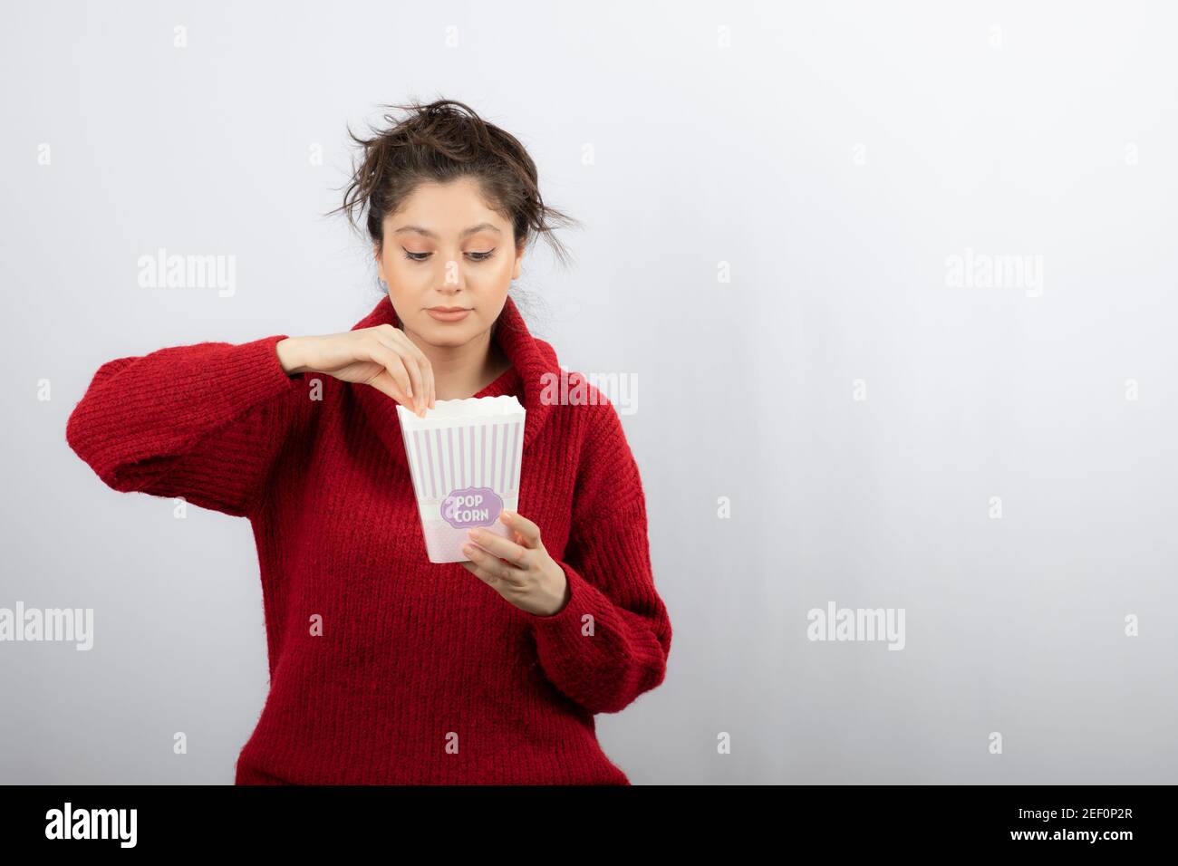 Photo of a cute woman looking into a bucket with popcorn Stock Photo ...