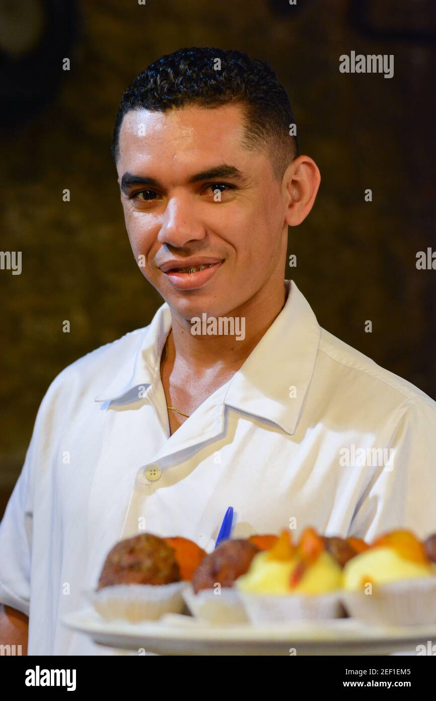 RIO DE JANEIRO, BRAZIL - JANUARY 3, 2020: A waiter holds a tray of ...