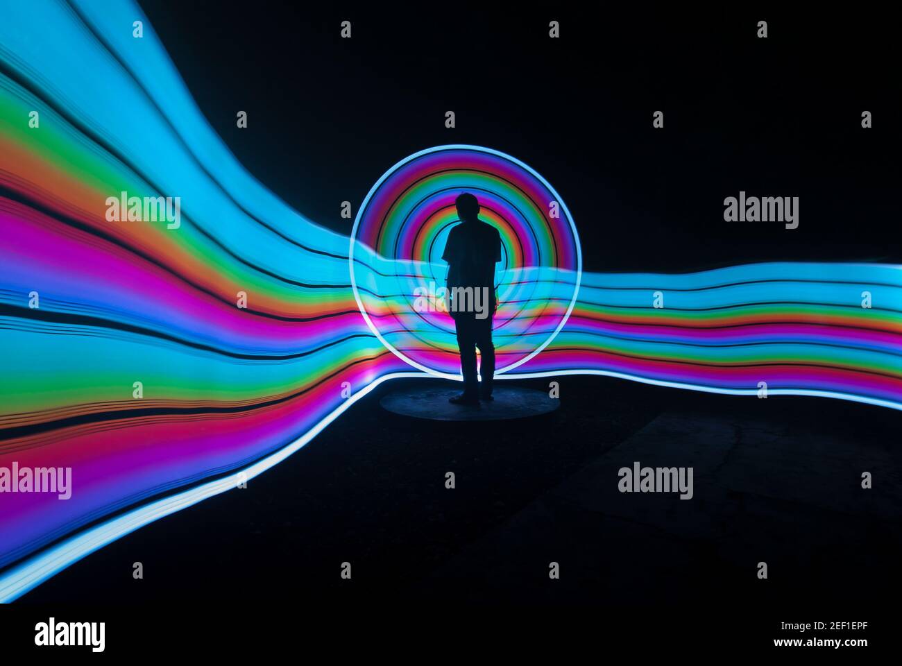 One person standing alone against beautiful color circle LED light ...