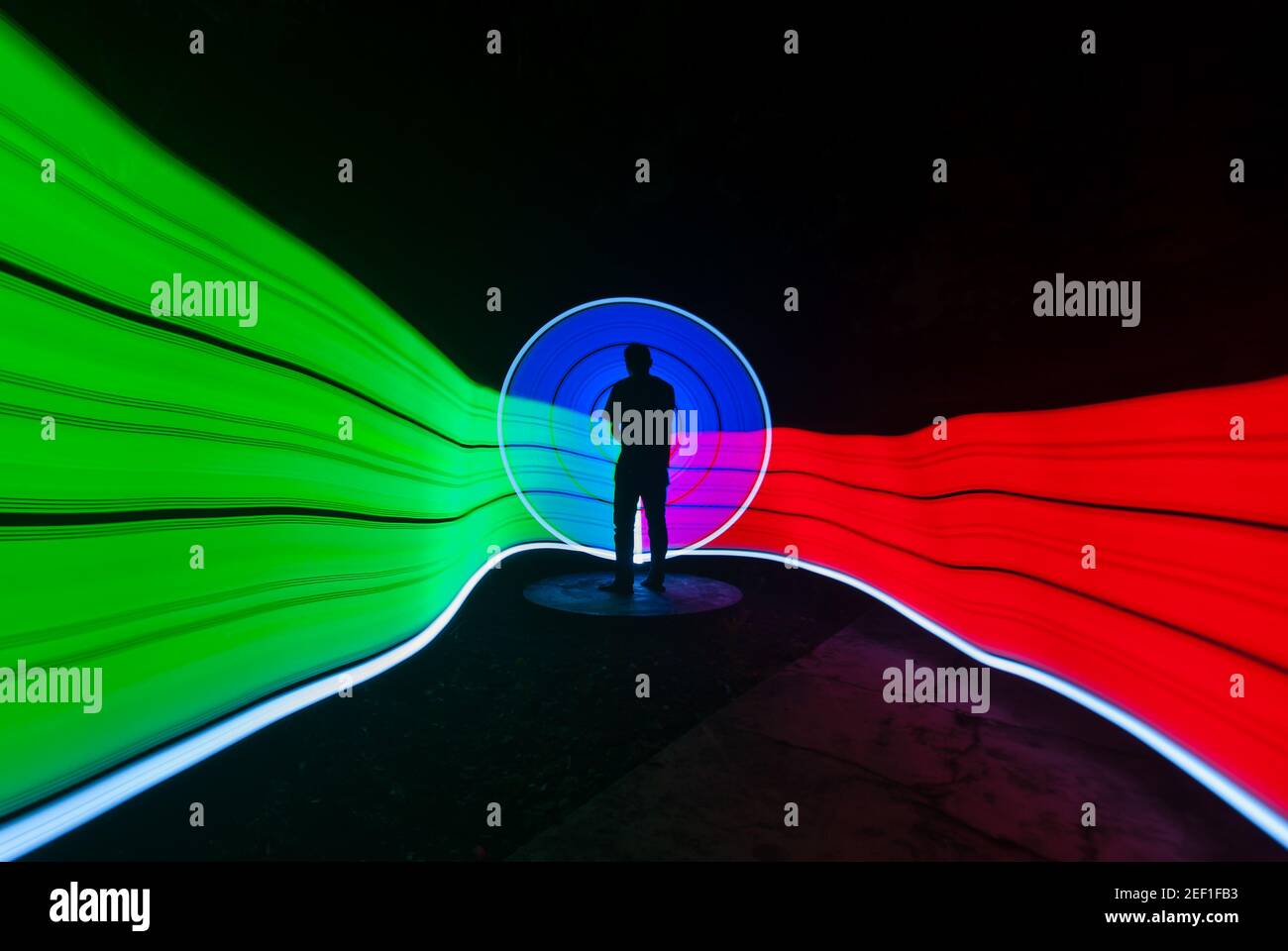One person standing alone against beautiful color circle LED light ...
