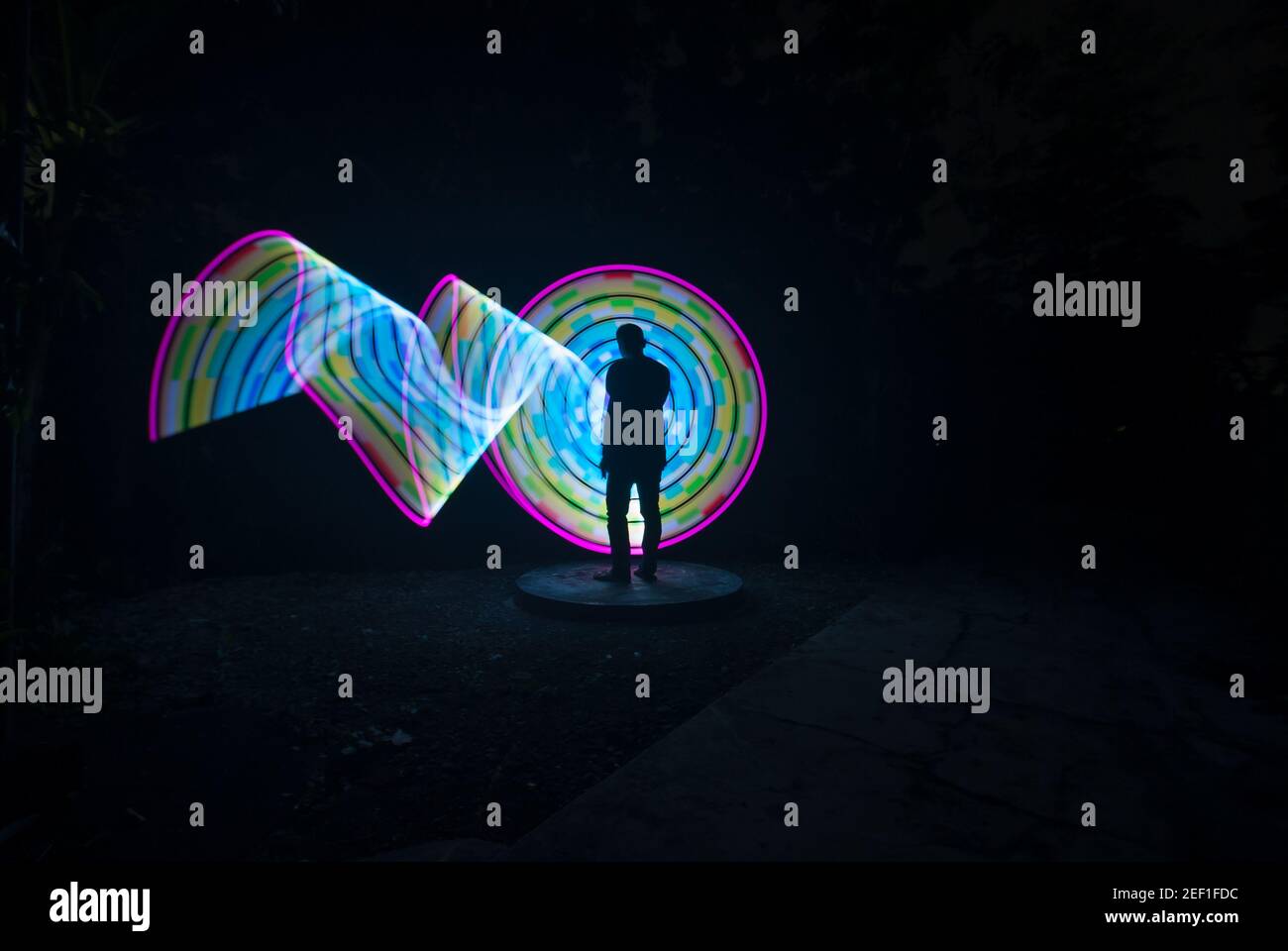 One person standing alone against beautiful color circle LED light ...