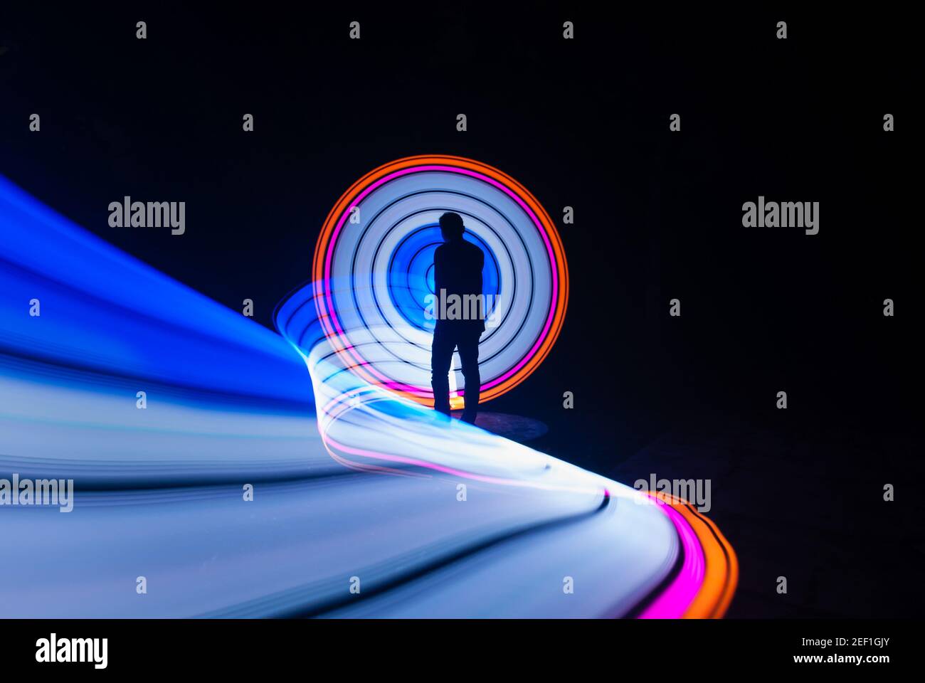 One person standing alone against beautiful color circle LED light ...