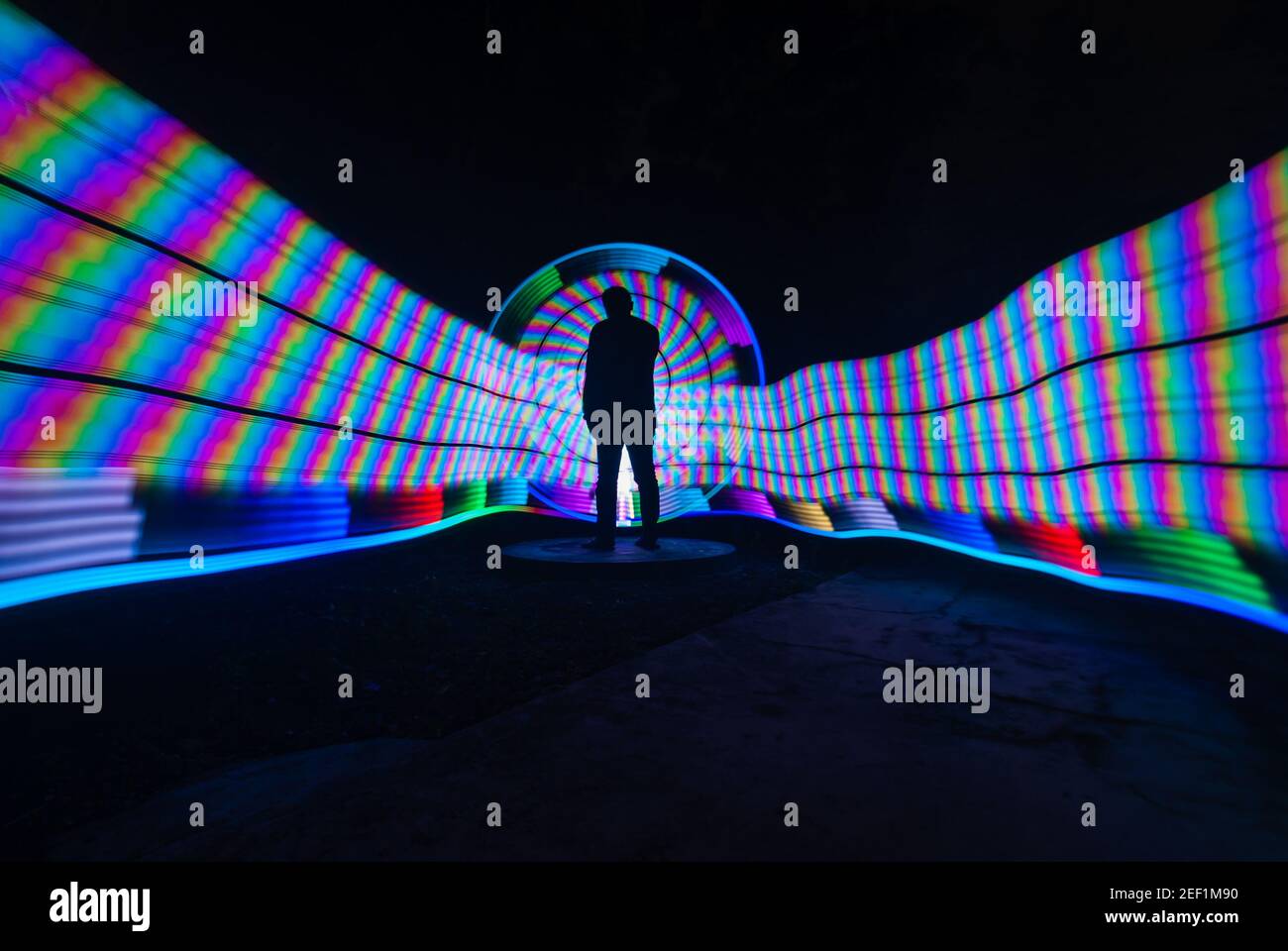 One person standing alone against beautiful color circle LED light ...