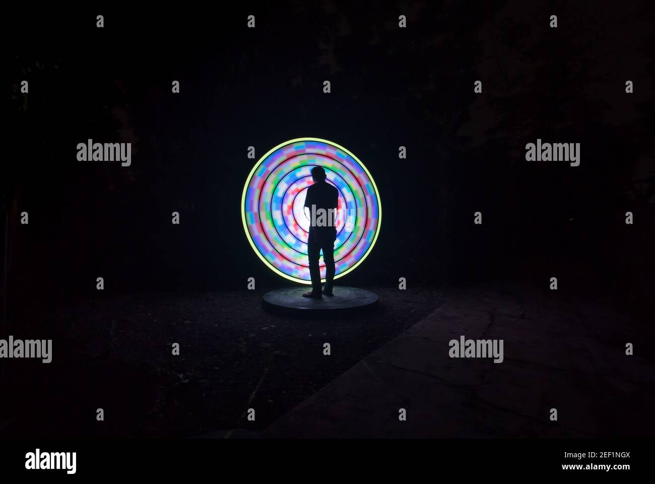 One person standing alone against beautiful color circle LED light ...