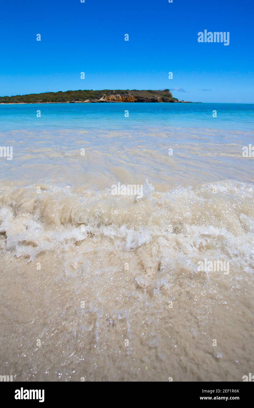 Idyllic beach scene with clear blue water, blue sky and sandy shore ...