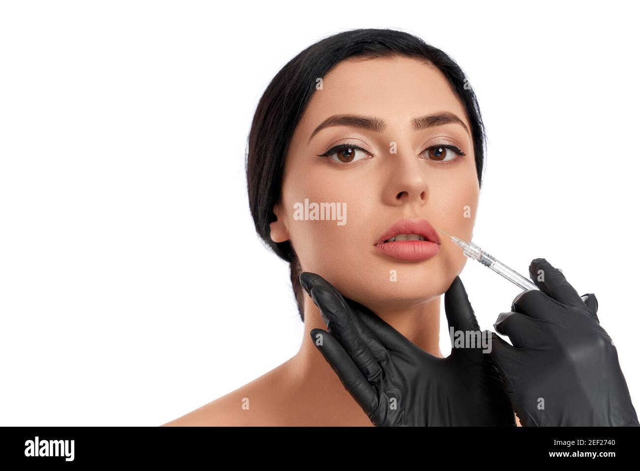 Close up of beautician hands in medical gloves doing beauty injection for charming young woman ...