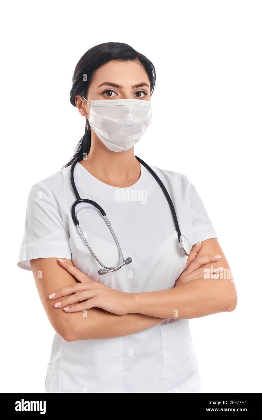 Competent female doctor wearing medical uniform and face mask standing ...