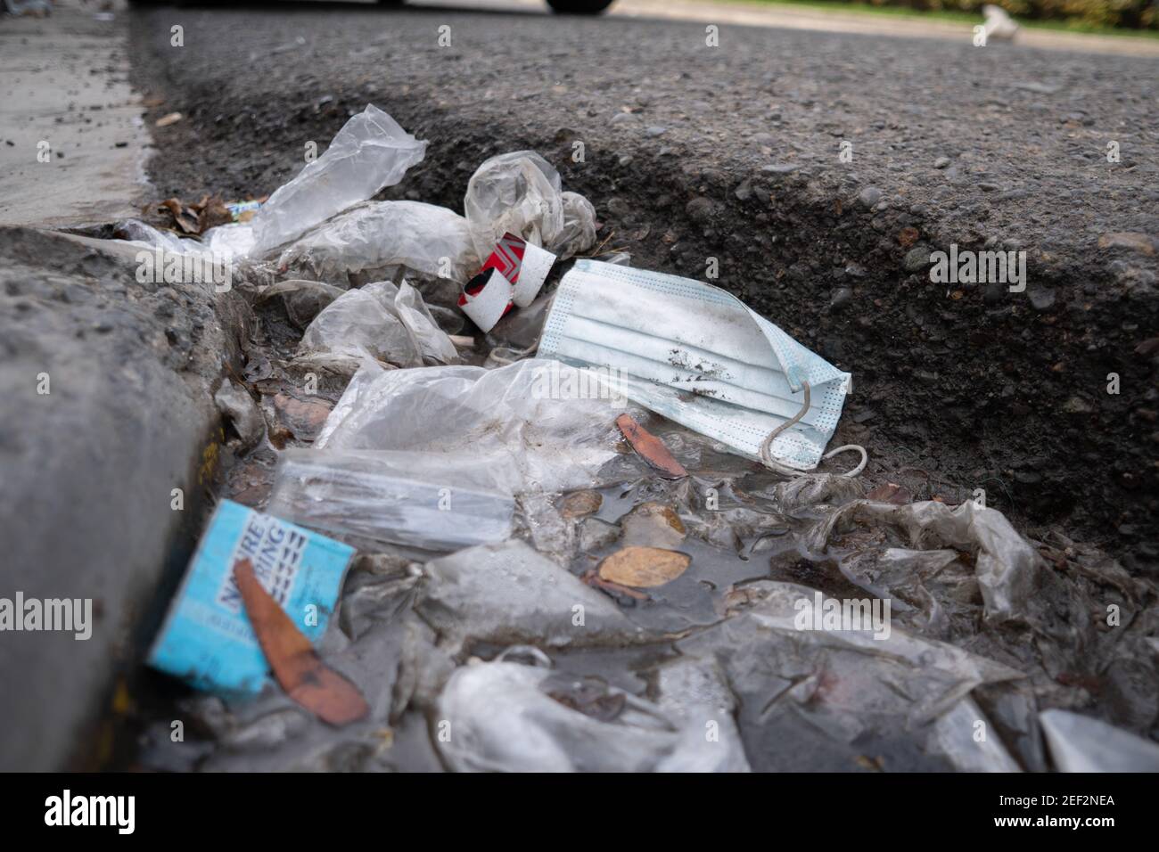 A discarded face mask lying at the kerbside of a road with other ...