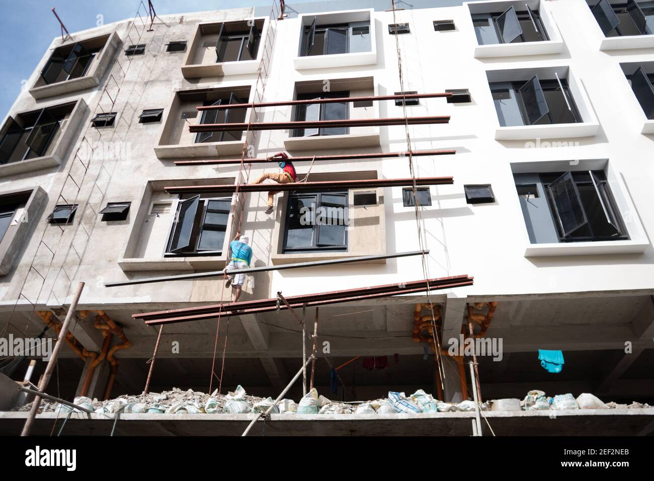 Two men in the Philippines using improvised scaffolding to work on a ...