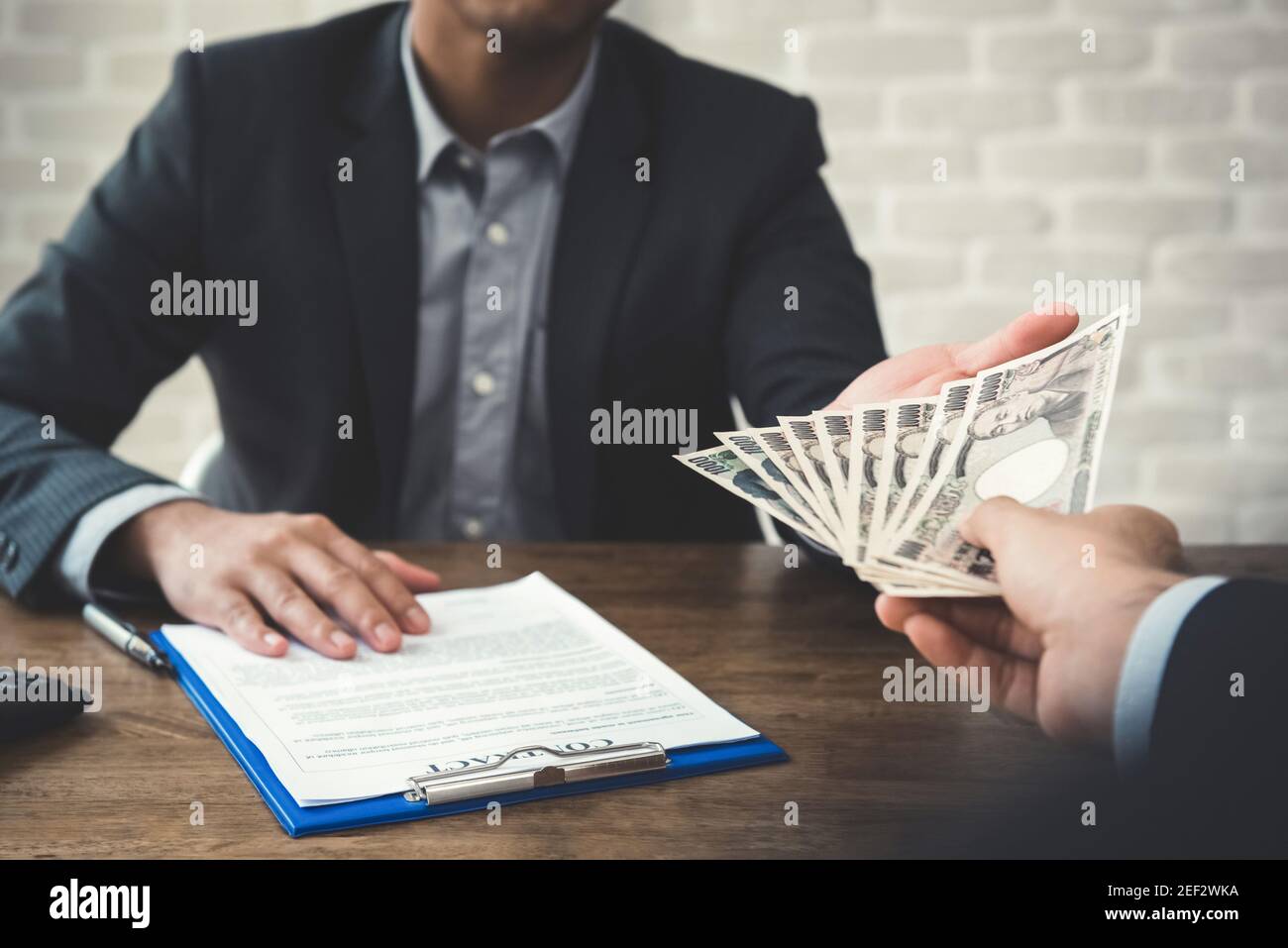 Businessman giving money, Japanese Yen, to his partner while making an ...