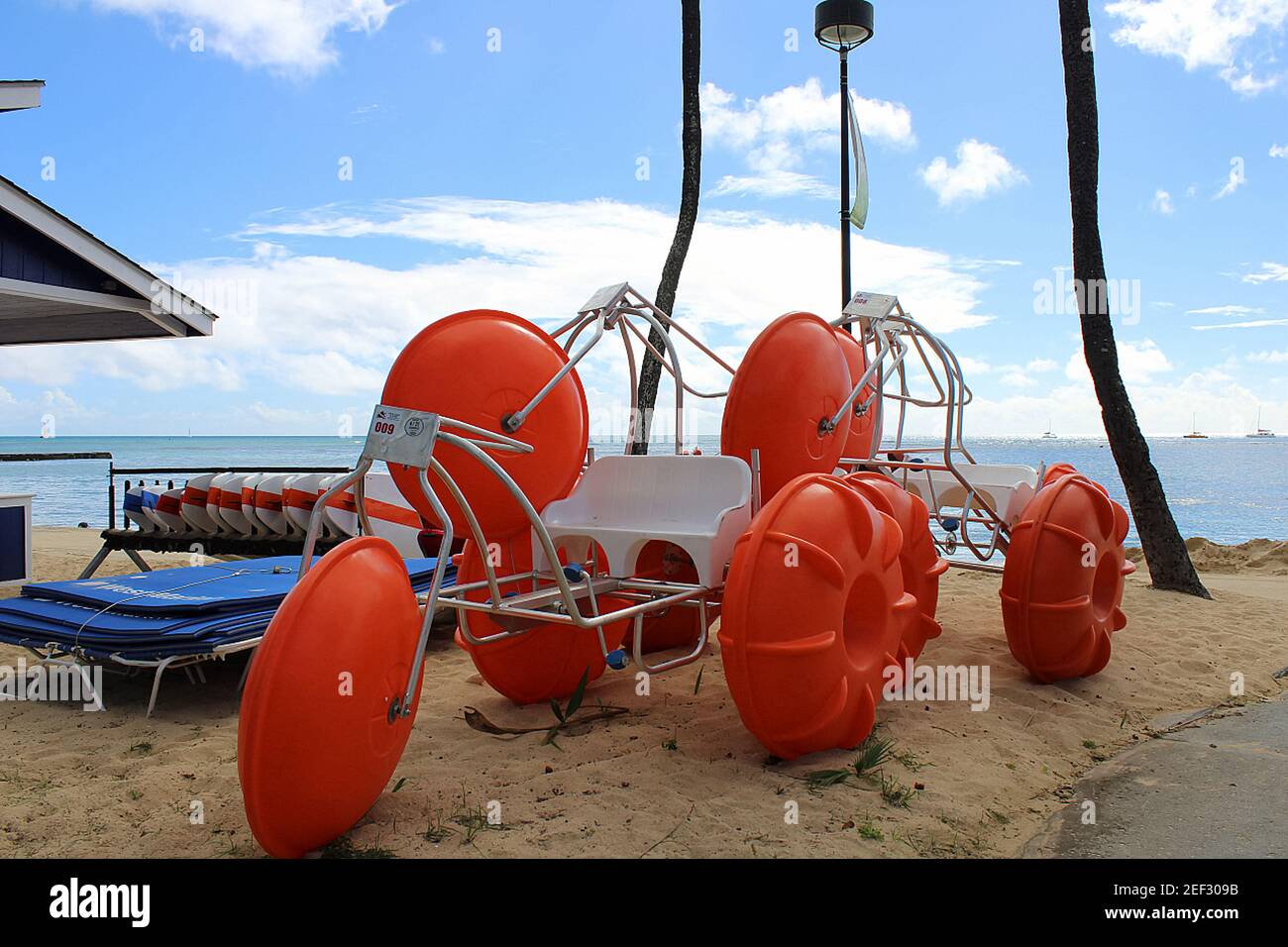 Water tricycles, blue floating matts, and surf boards stacked on a ...