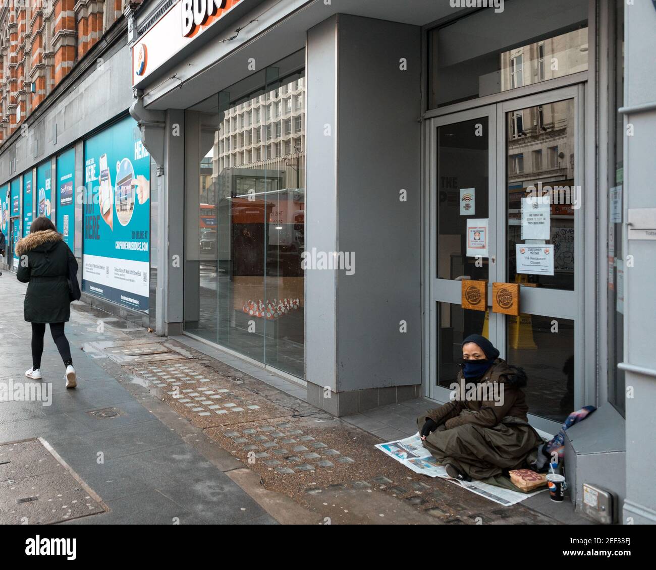 Homeless, unemployed woman taking shelter in front of a closed Burger ...