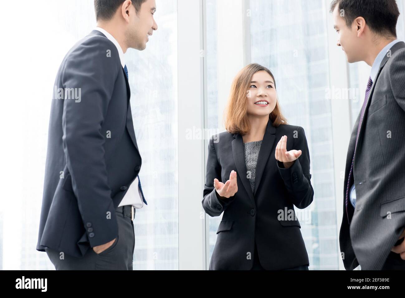 Asian businesswoman talking with her team in office building hallway ...